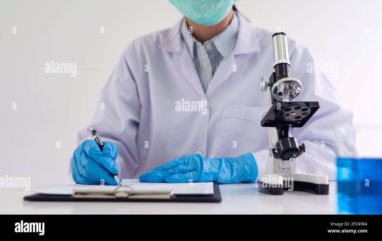 scientists researching in laboratory in white lab coat, gloves ...