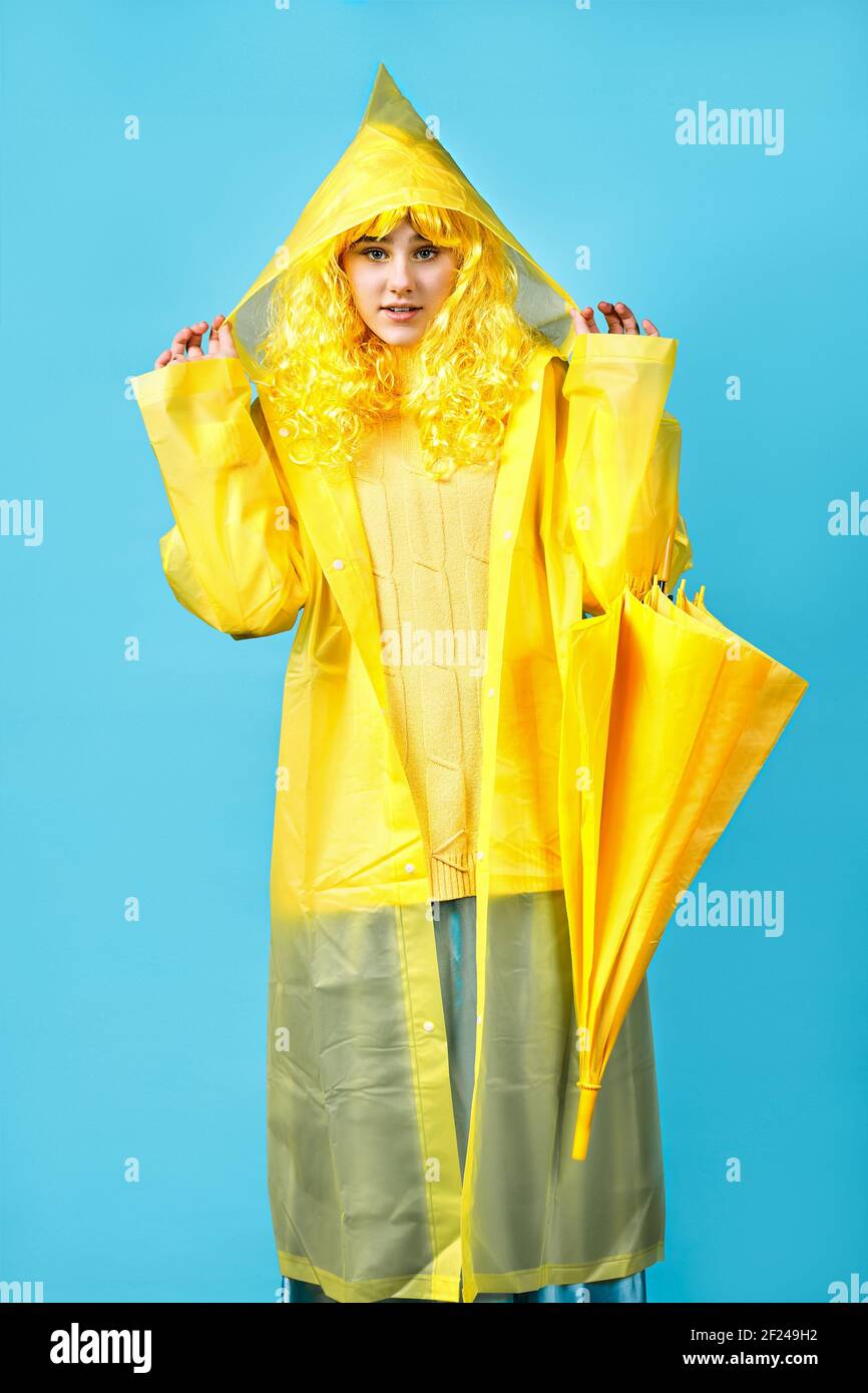 pretty teen girl in a yellow raincoat with an umbrella and a hood on ...