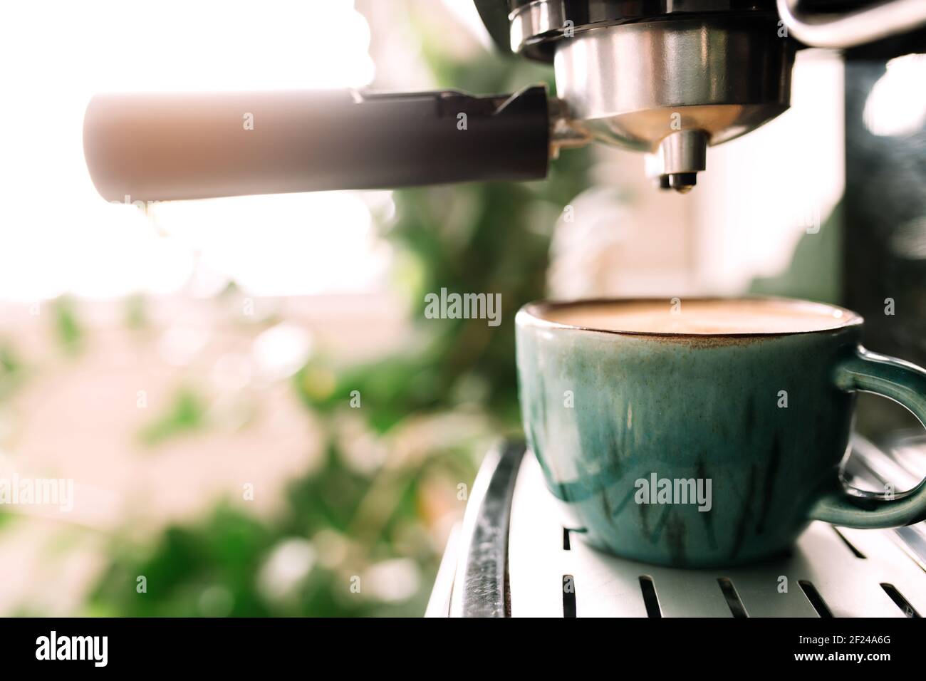 Green cup of coffee at the coffee maker machine, coffee time. Blurred ...