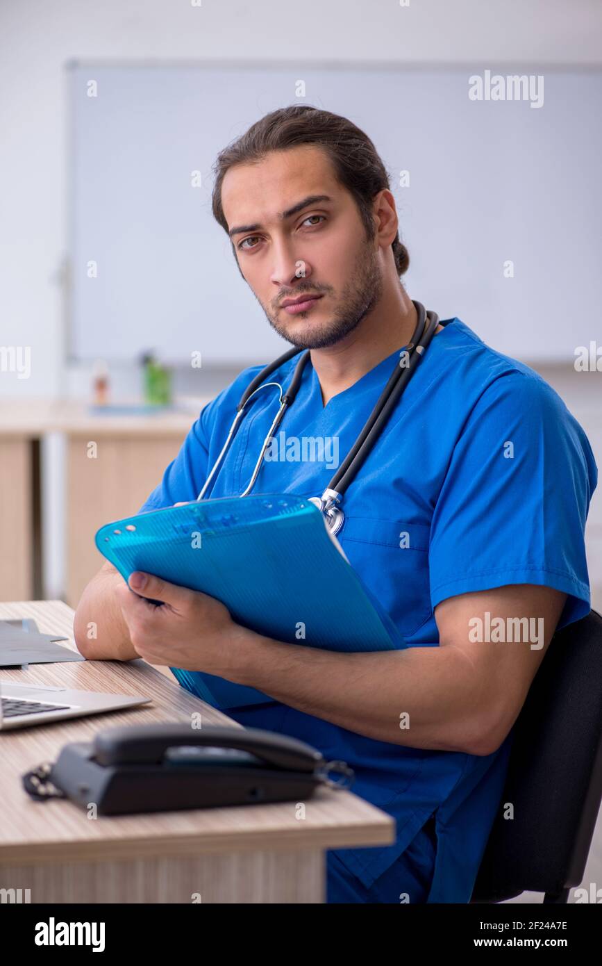 Young male doctor taking notes in the clinic Stock Photo - Alamy