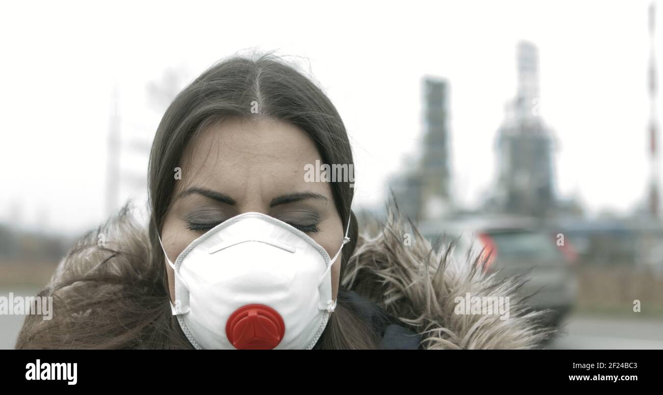 Woman wearing air pollution mask against smog, with urban industrial ...