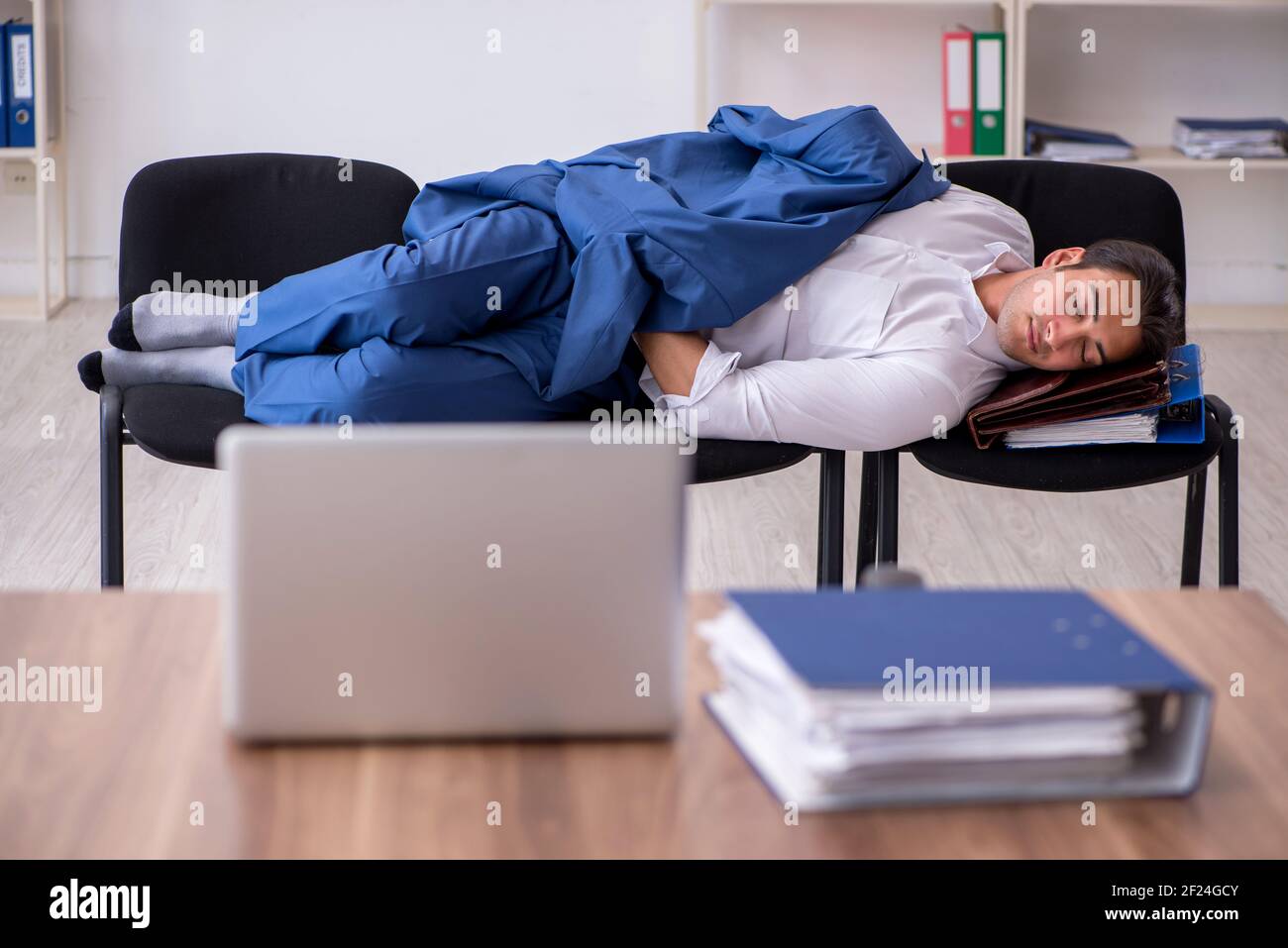 Young male employee sleeping in the office on chairs Stock Photo - Alamy