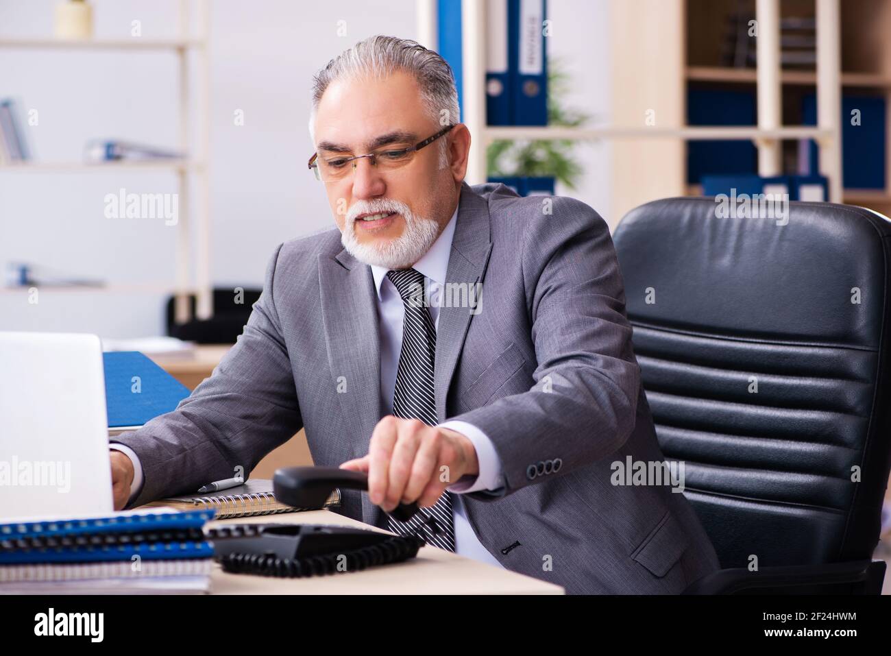 Old male employee using phone in the office Stock Photo - Alamy