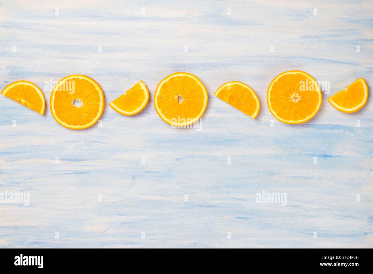 A top view of tasty orange slices in a line isolated on the blue-white ...
