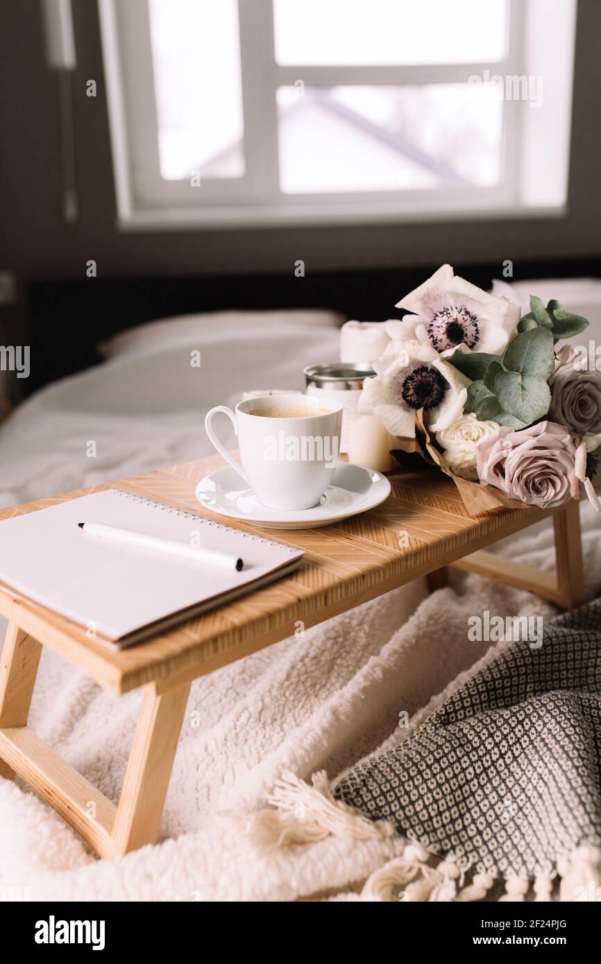 Romantic morning. Wooden coffee table with flowers on bed with plaid ...