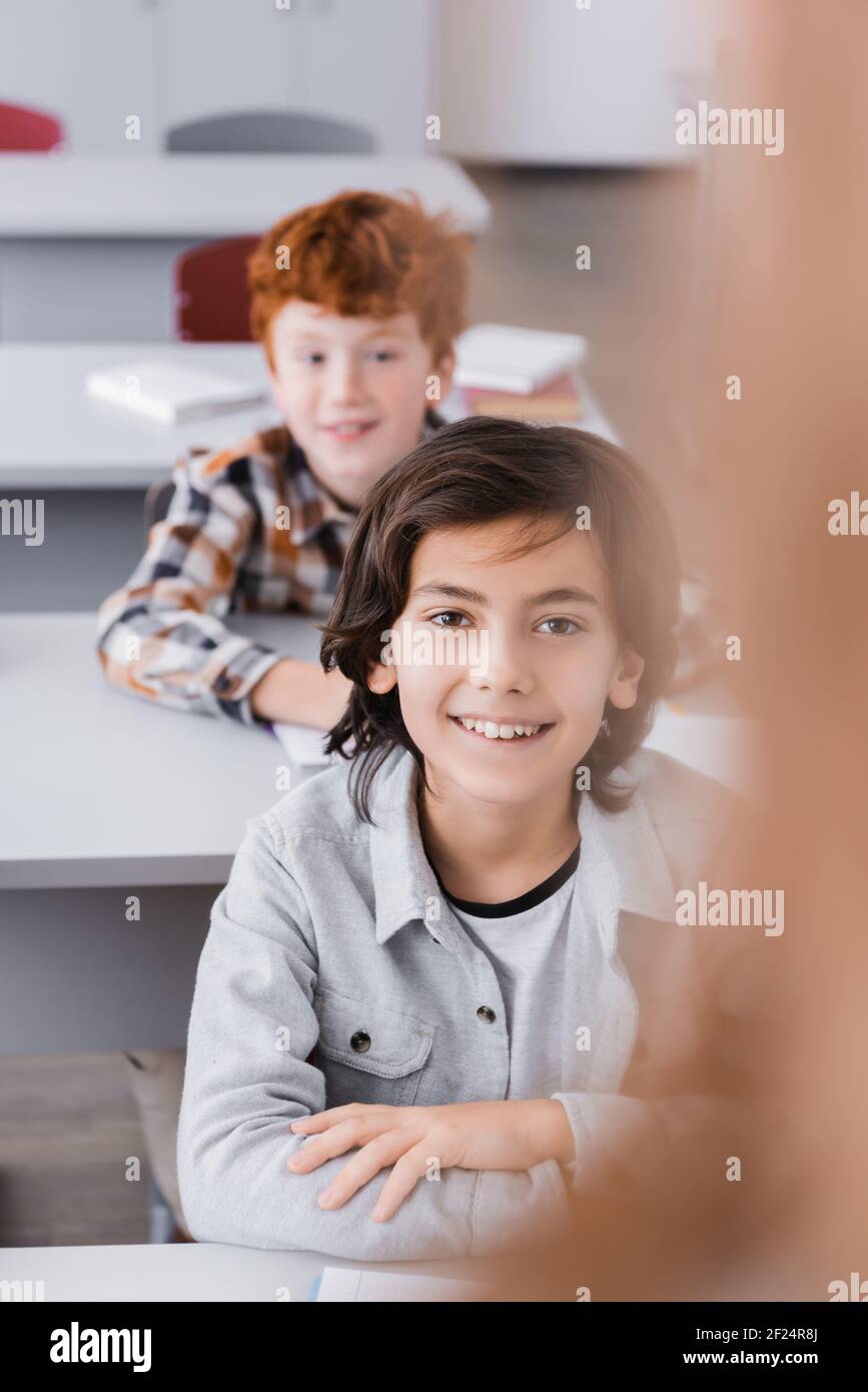 cheerful boy looking at camera in classroom on blurred foreground Stock ...