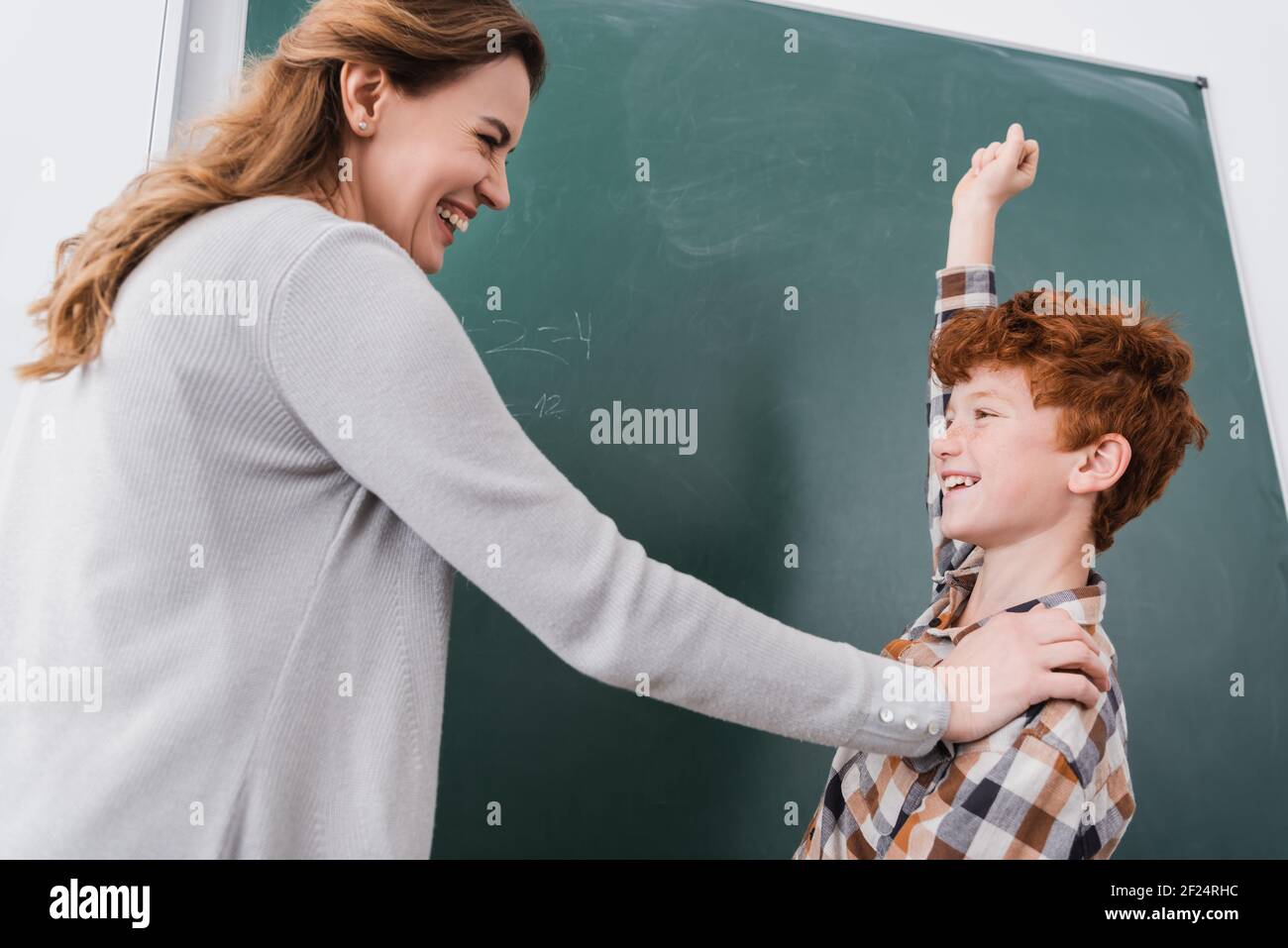 excited schoolboy showing win gesture near chalkboard and happy teacher ...