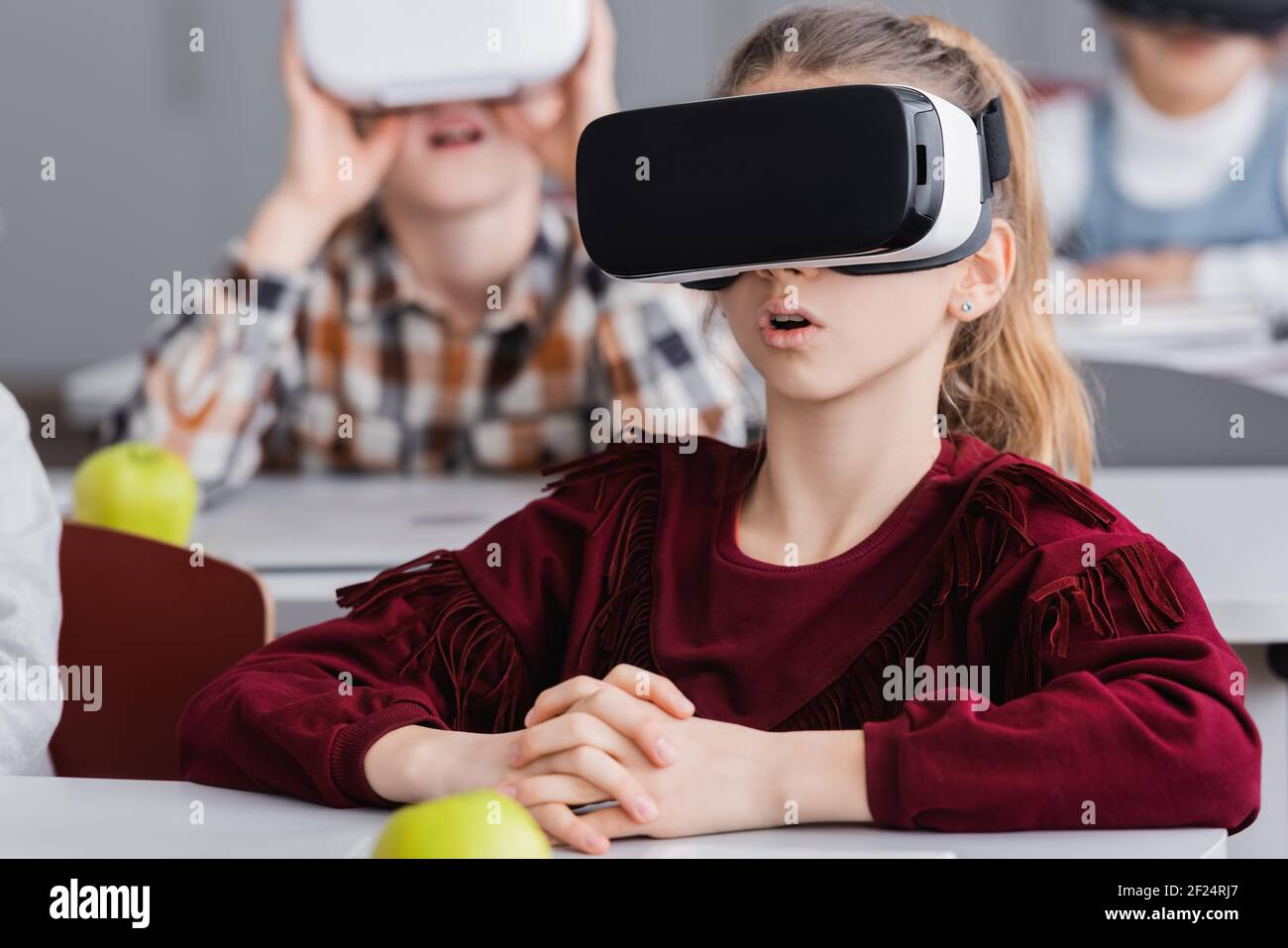 Amazed Schoolgirl Gaming In Vr Headset Near Classmates On Blurred 0996