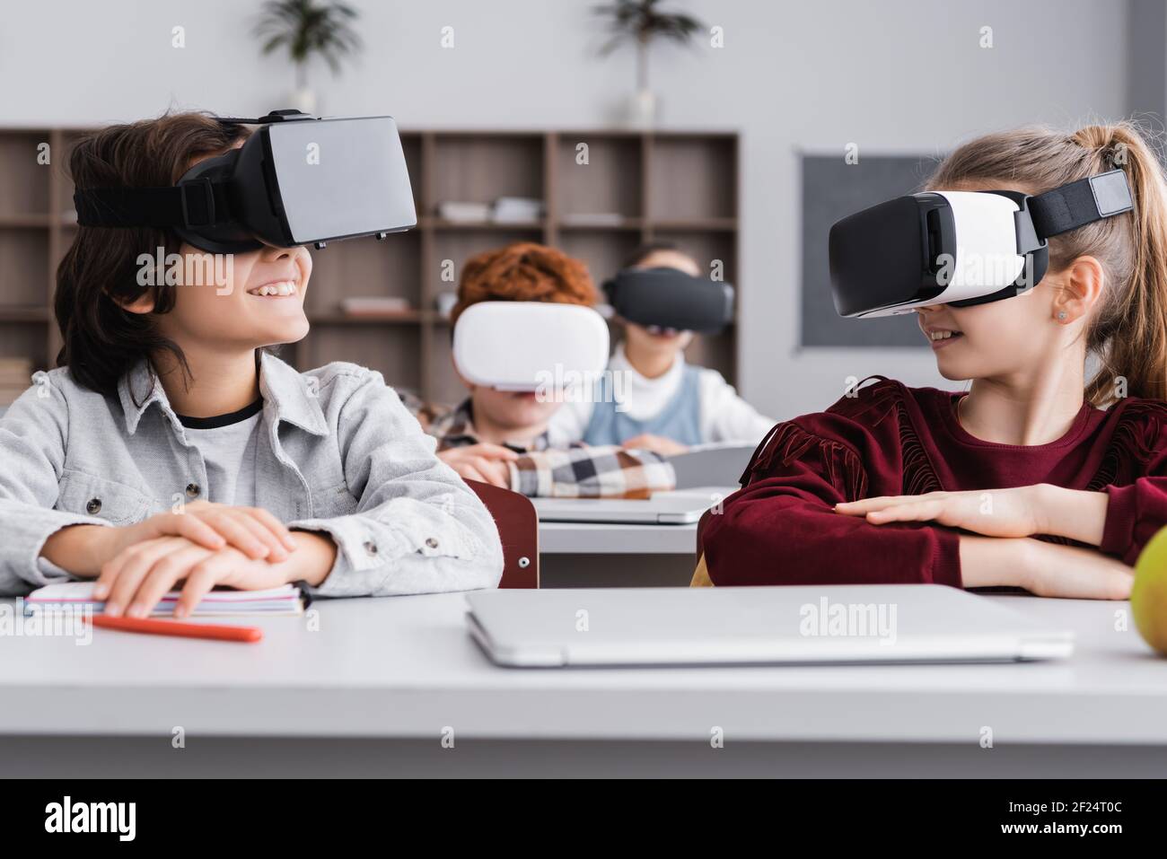 happy classmates looking at each other while gaming in vr headsets in ...