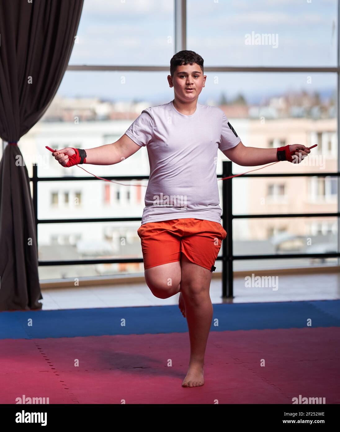 Overweight young man training in a boxing gym, jumping rope Stock Photo ...