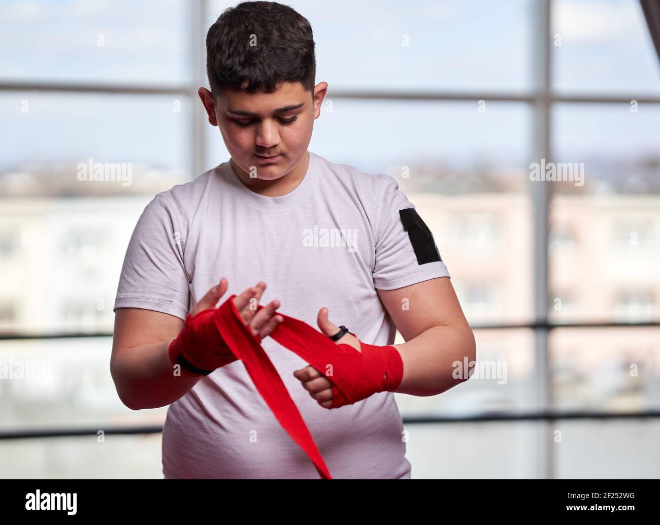 Overweight young boxer wrapping his hands before training Stock Photo ...