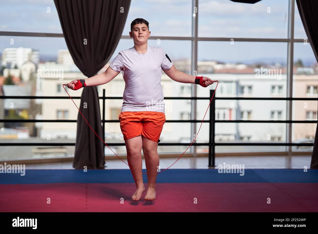 Overweight young man training in a boxing gym, jumping rope Stock Photo ...