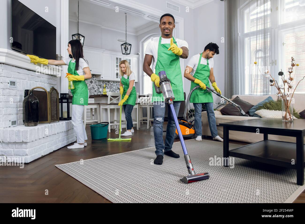 Four multicultural janitors doing cleaning at room Stock Photo - Alamy