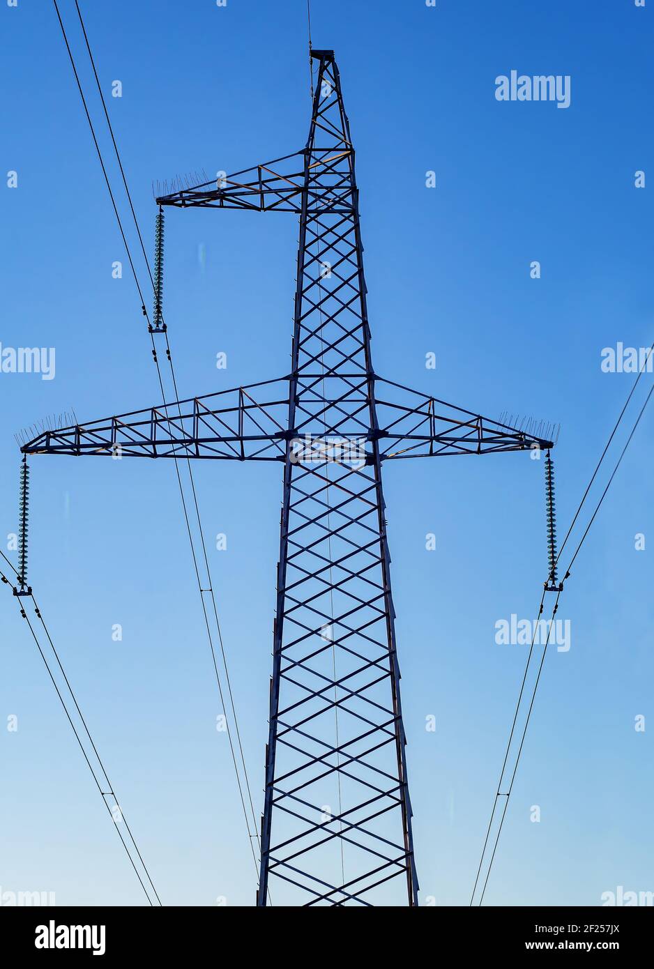 Metal support for power transmission lines 110/35/10 kV with wires and insulators against a blue ...