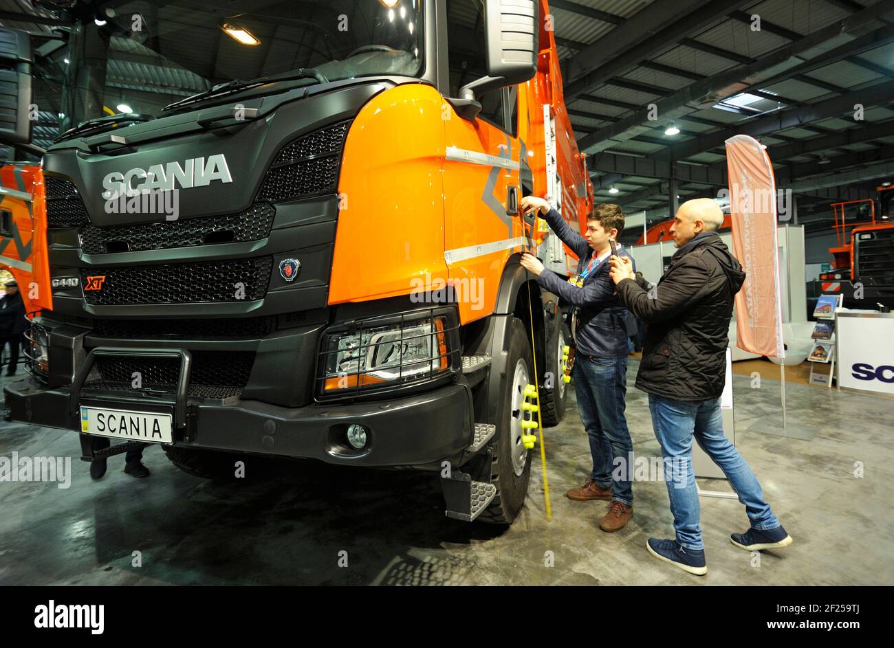 Men measuring sizes of a new model of a dump truck Scania parked on a ...