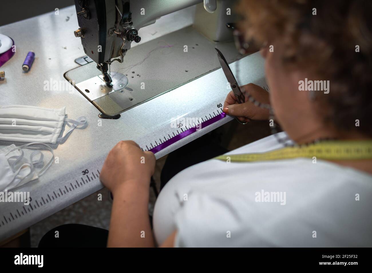 An adult female measuring a purple ribbon on a ruler in a workshop ...