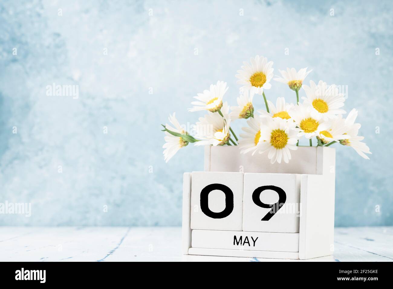 White cube calendar for may decorated with daisy flowers over blue ...