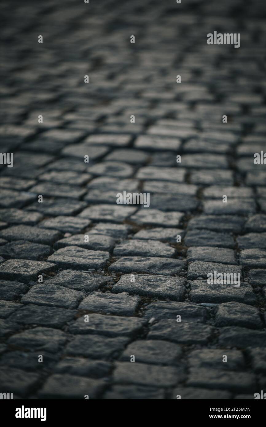 A vertical shot of the black cobbled stone road with small pebbles ...