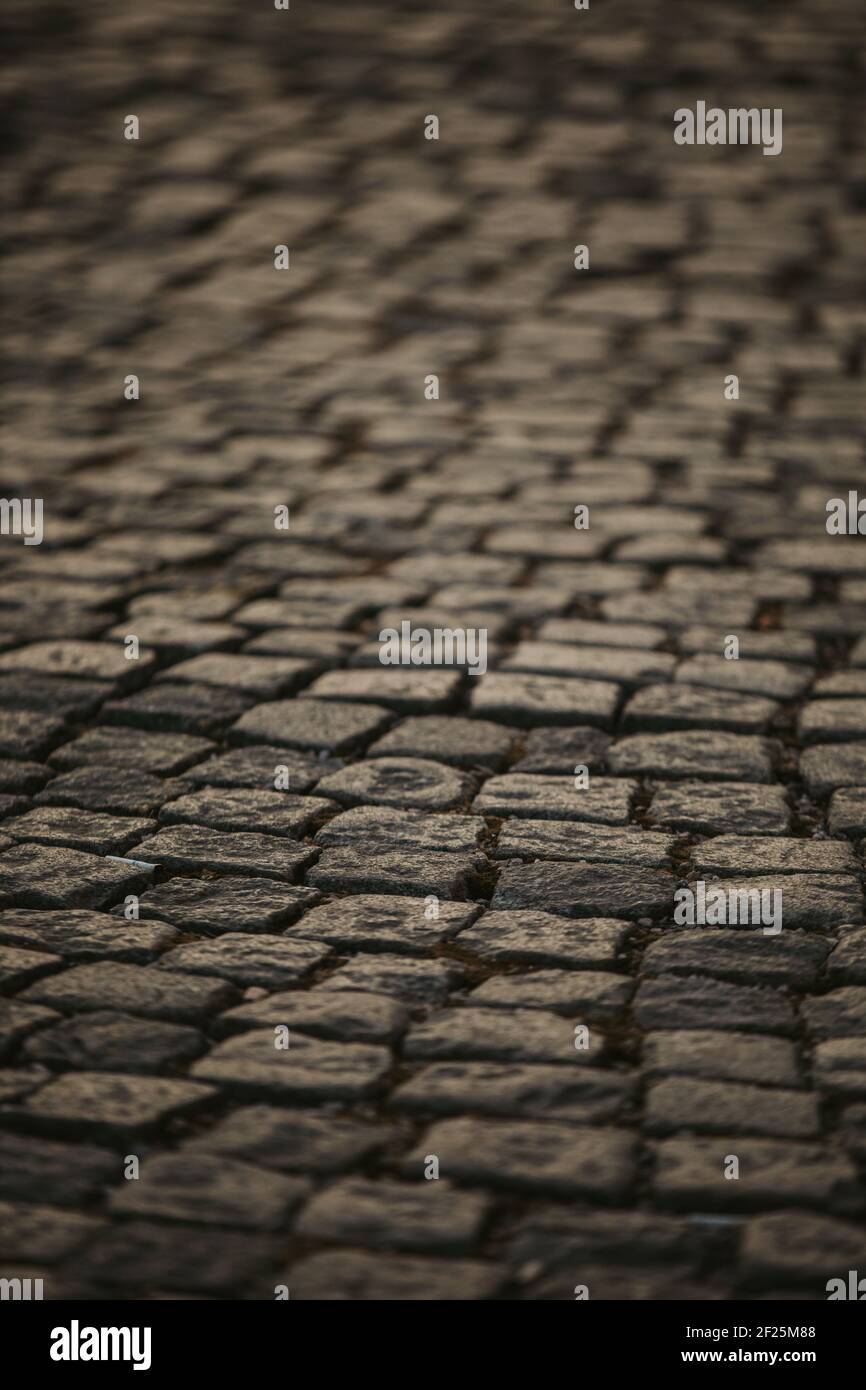 A vertical shot of the black cobbled stone road with small pebbles ...
