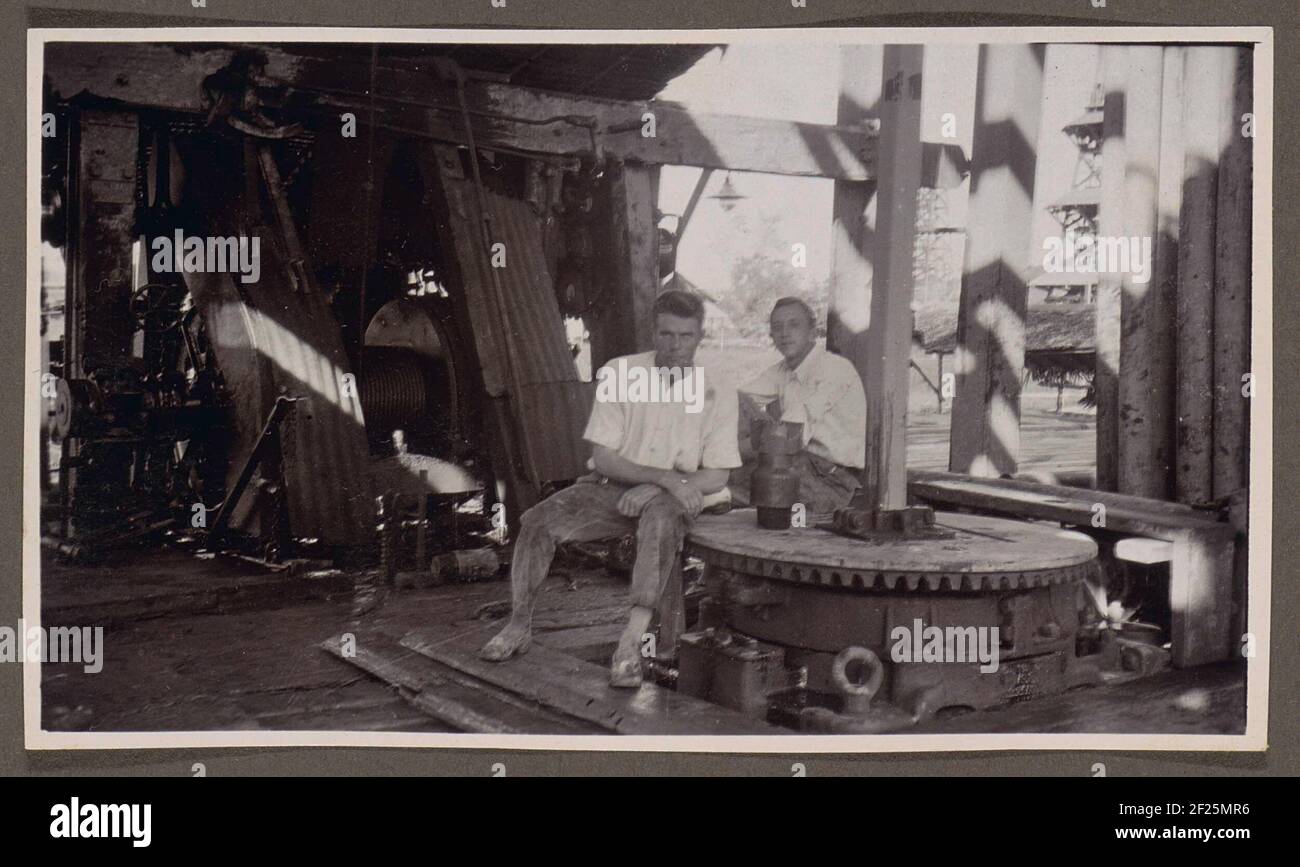 Two men sitting in a derrick. Part of Family Album Dutch East Indies ...