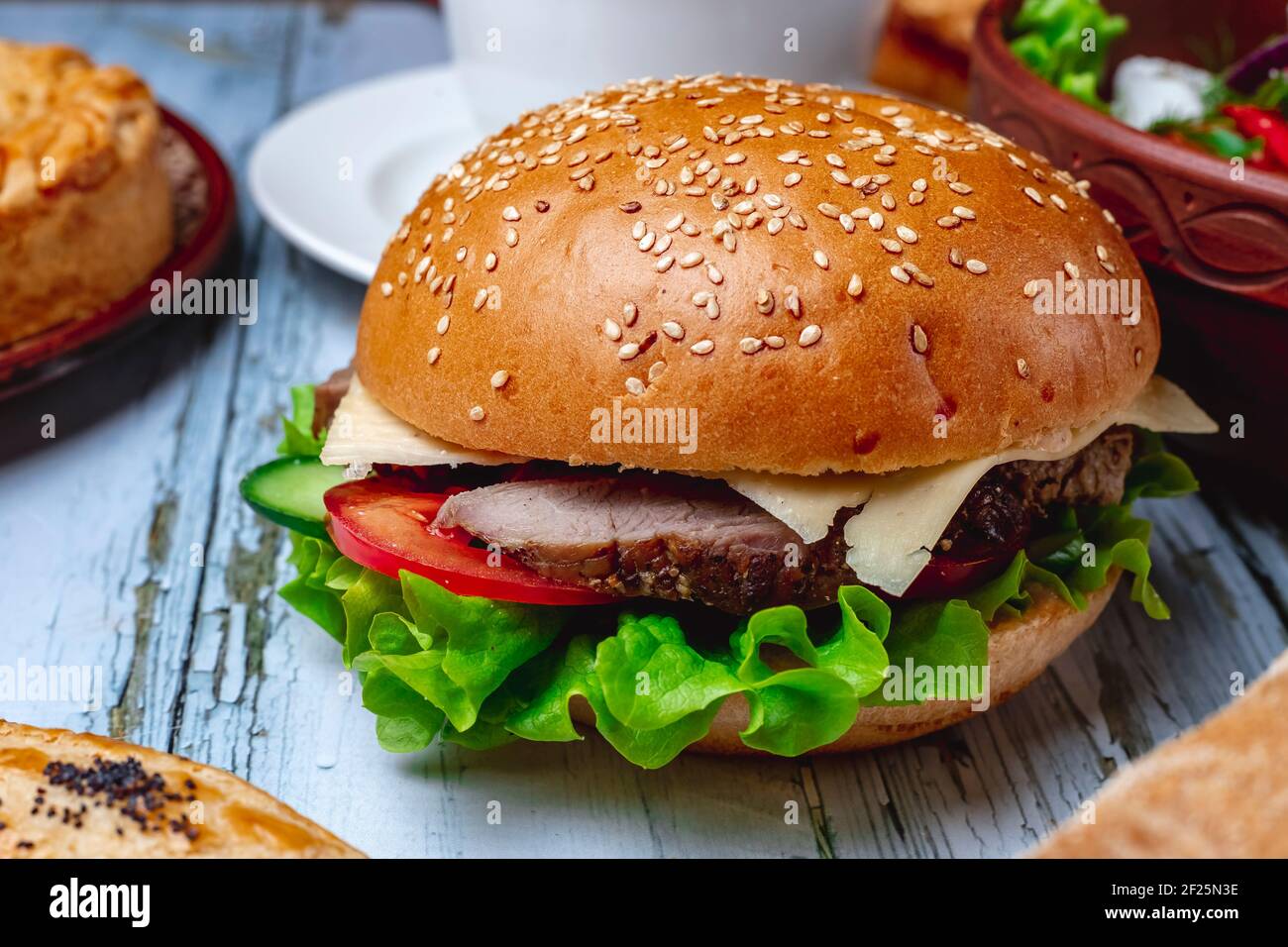 side view hamburger with grilled meat cheese lettuce and tomato between ...
