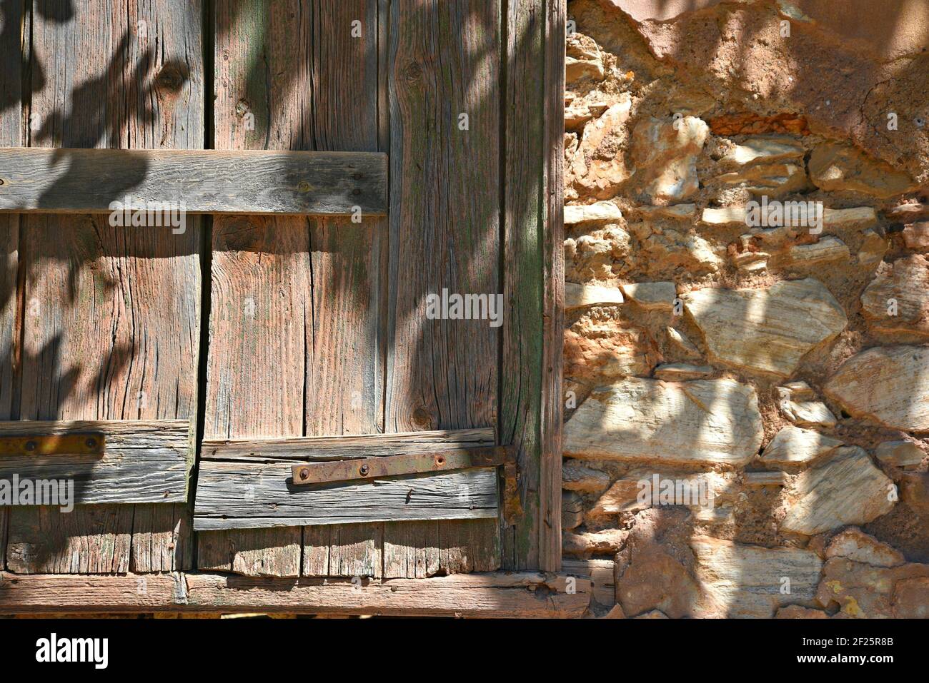 Antique wooden window shutters against a weathered stone wall in the ...