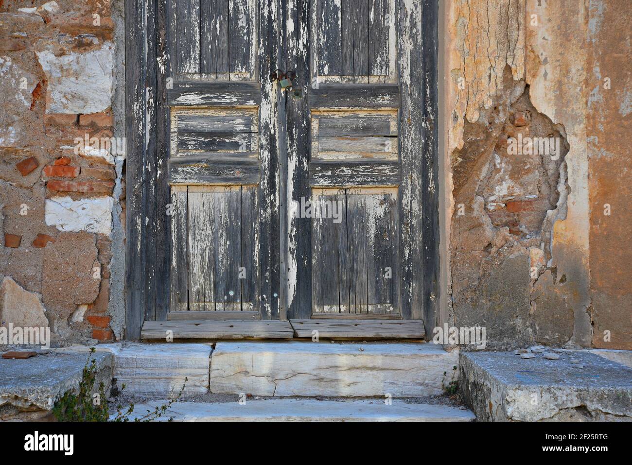Antique grey wooden entrance door with a white marble doorstep against ...