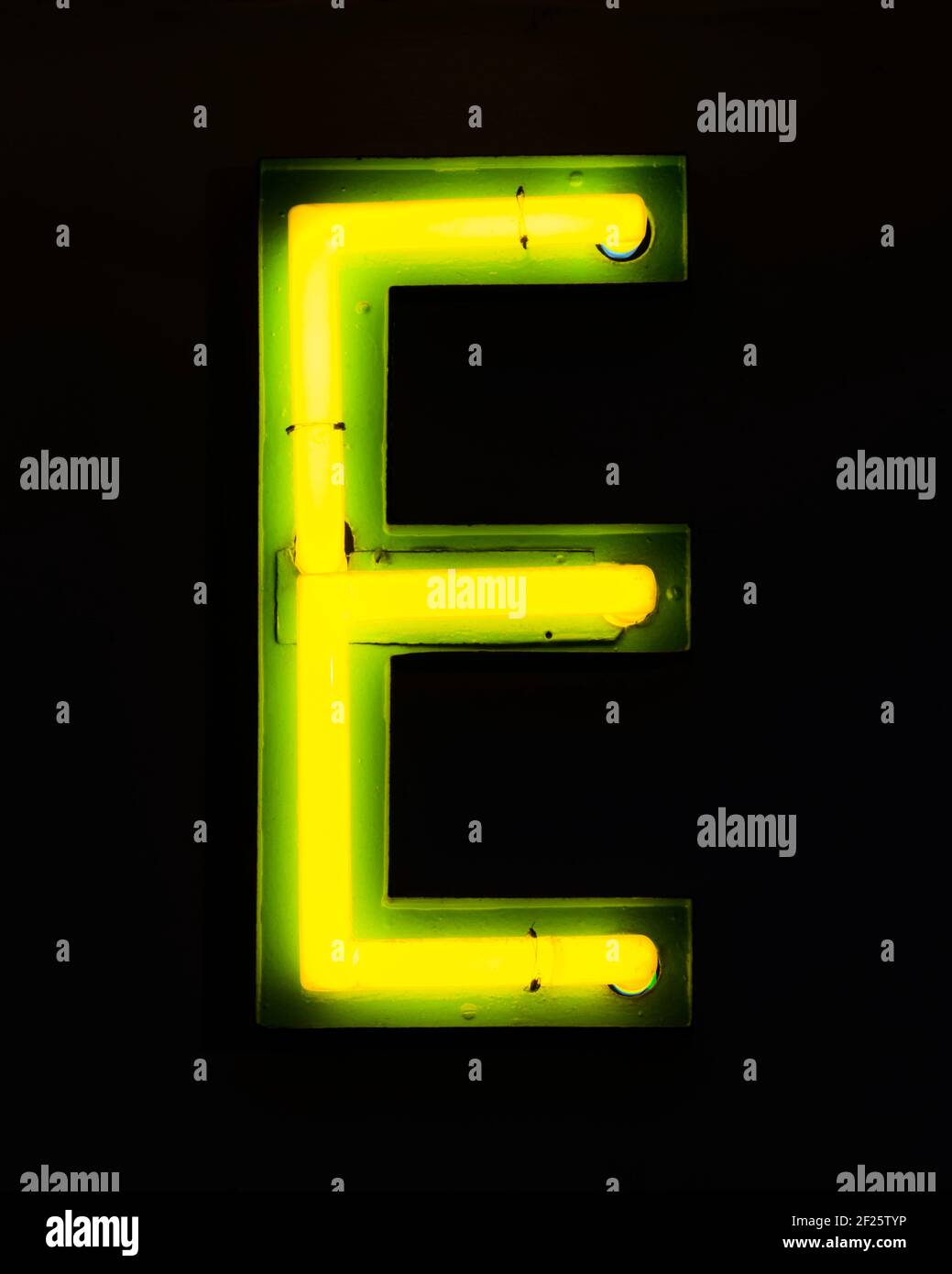 Yellow neon letter E glowing in the dark Stock Photo - Alamy