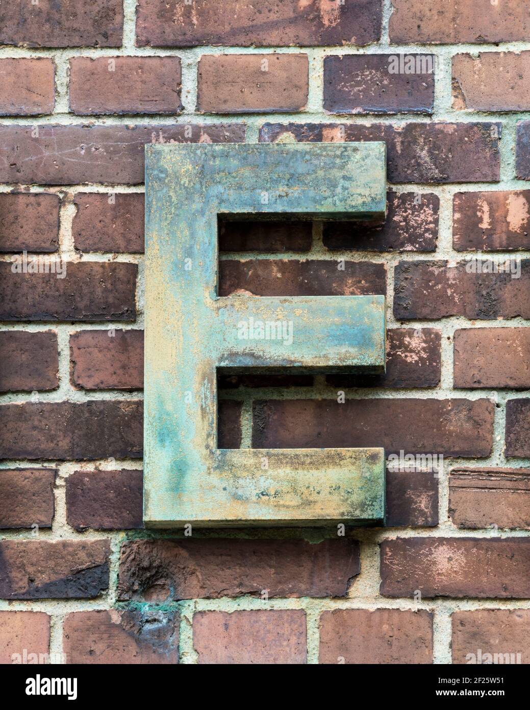 Weathered metal letter E in front of a brick wall Stock Photo - Alamy