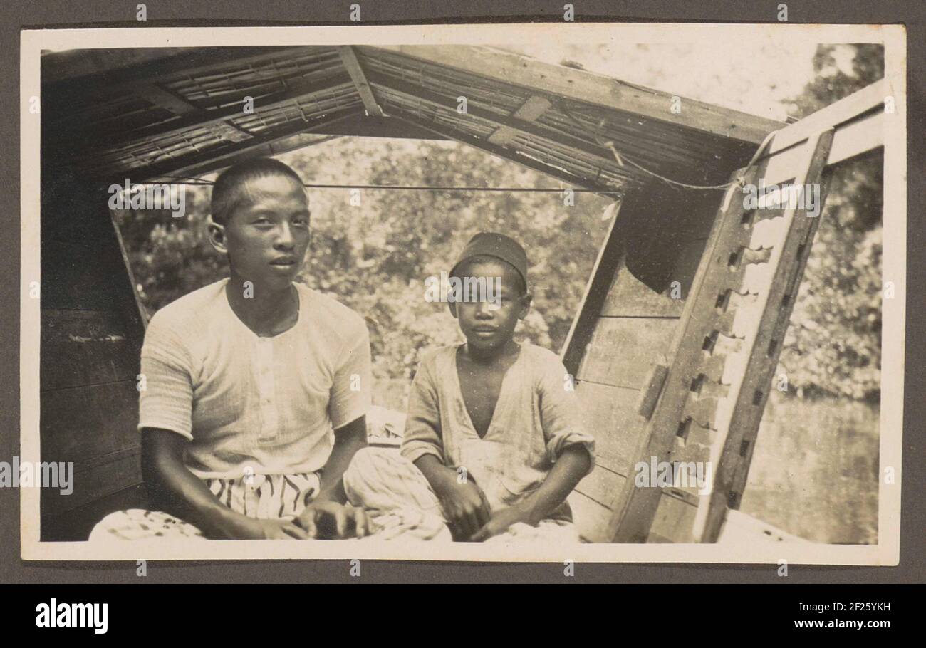Two Indian boys sitting in covered wooden boot.part or family album ...