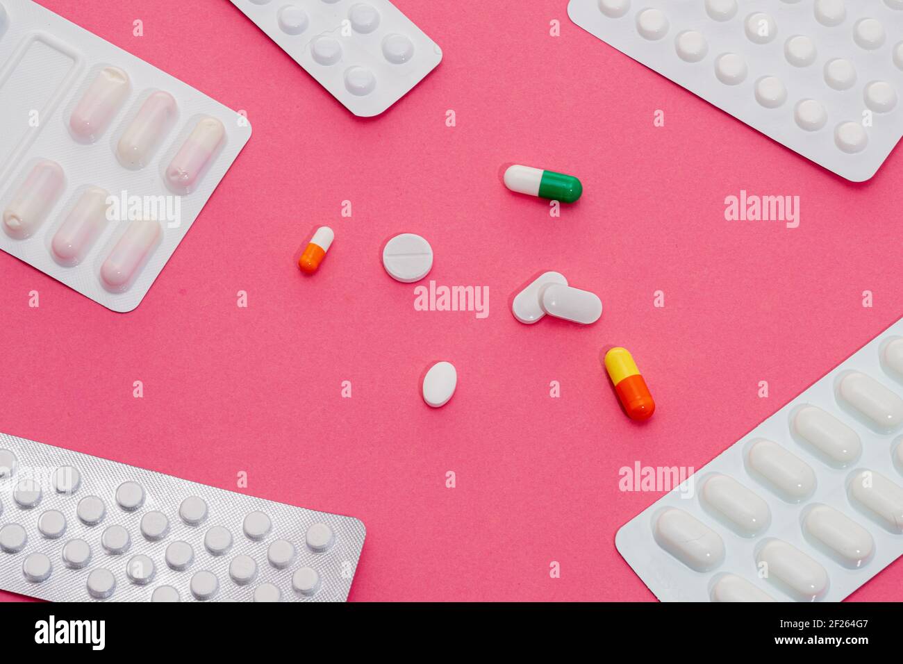 Assorted medicinal pills with blister packs placed on a pink background ...