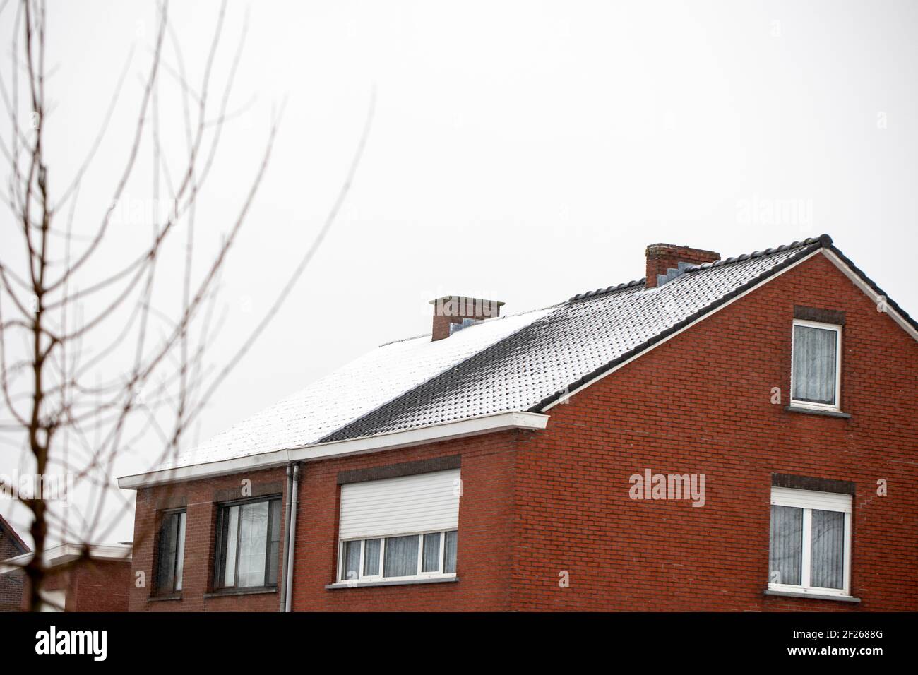 A portrait of two semi-detached buildings with white snow on their ...
