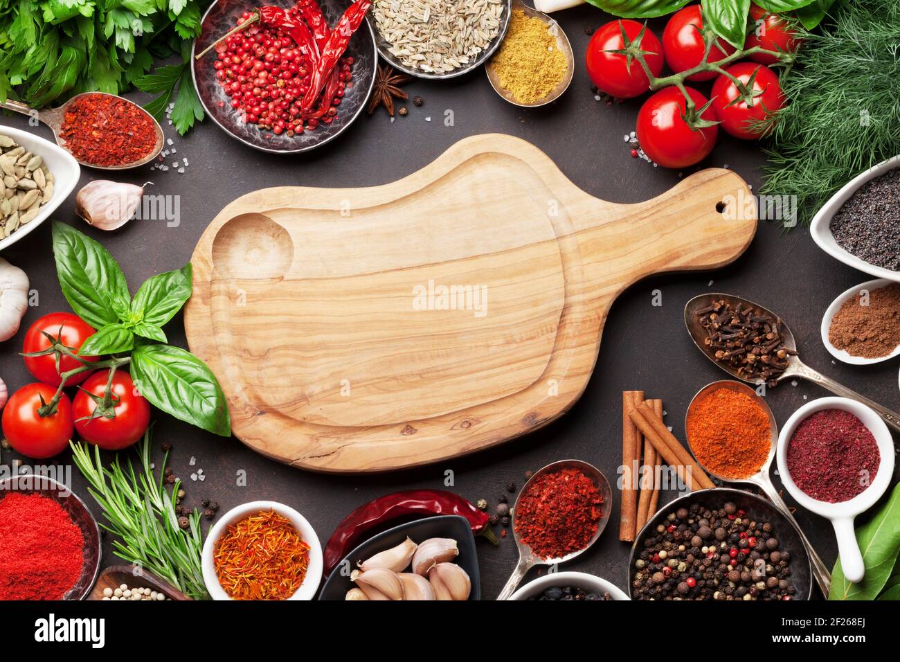 Various spices, herbs and cutting board on stone table. Top view with ...