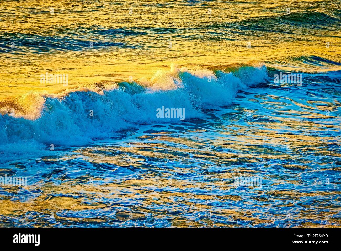 Golden sunlight reflecting off of ocean with breaking waves Stock Photo ...