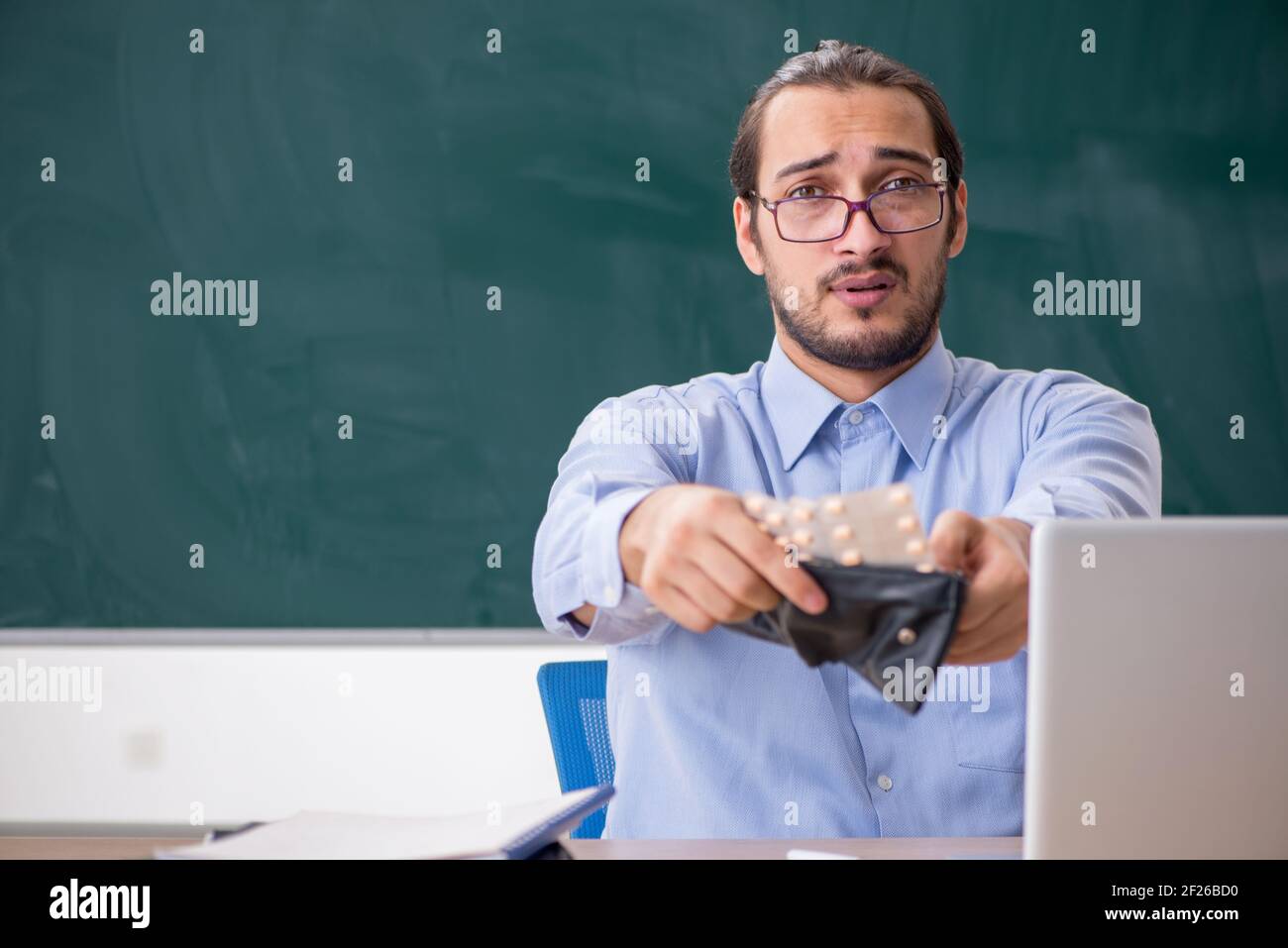 Young sick male teacher in the classroom Stock Photo - Alamy