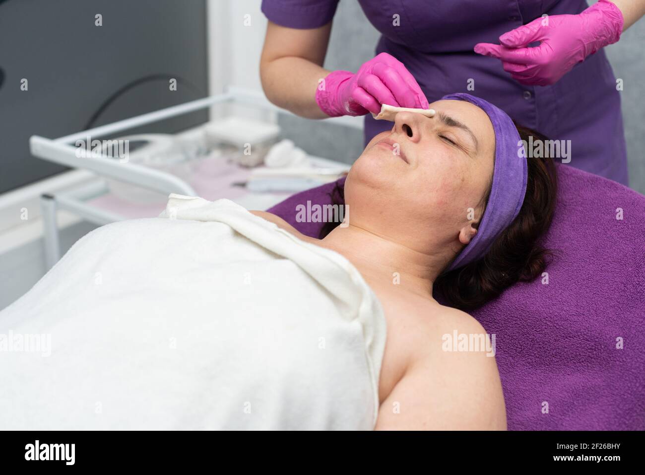 After washing the face with the gel, the beautician wipes dry the ...