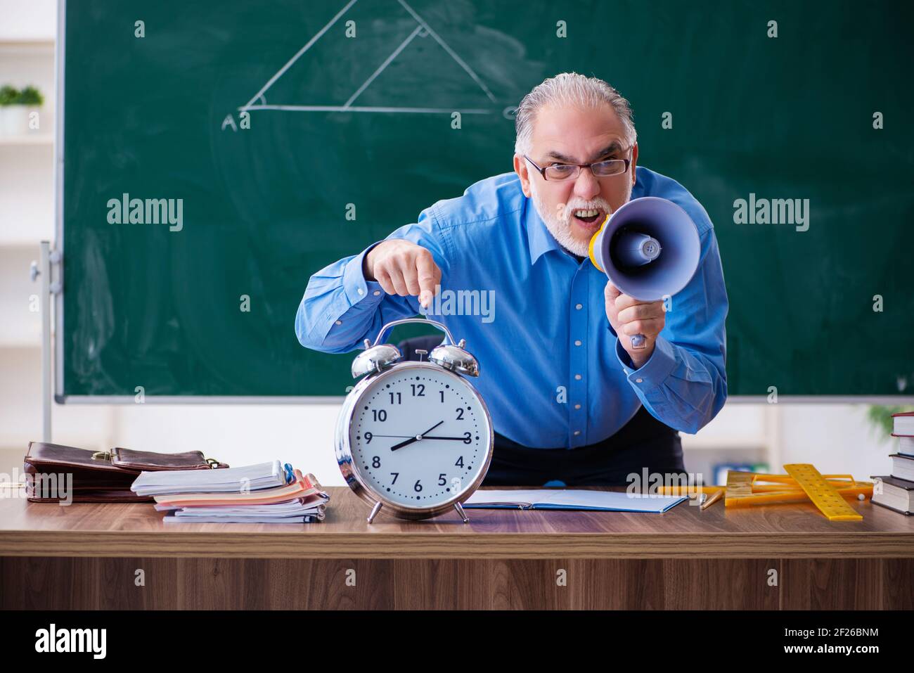 Old male math teacher in time management concept Stock Photo - Alamy