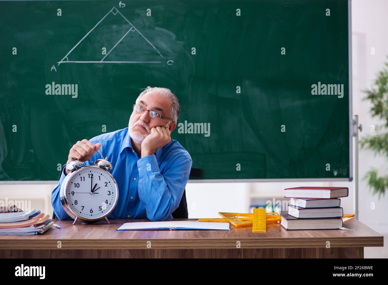 Old male math teacher in time management concept Stock Photo - Alamy