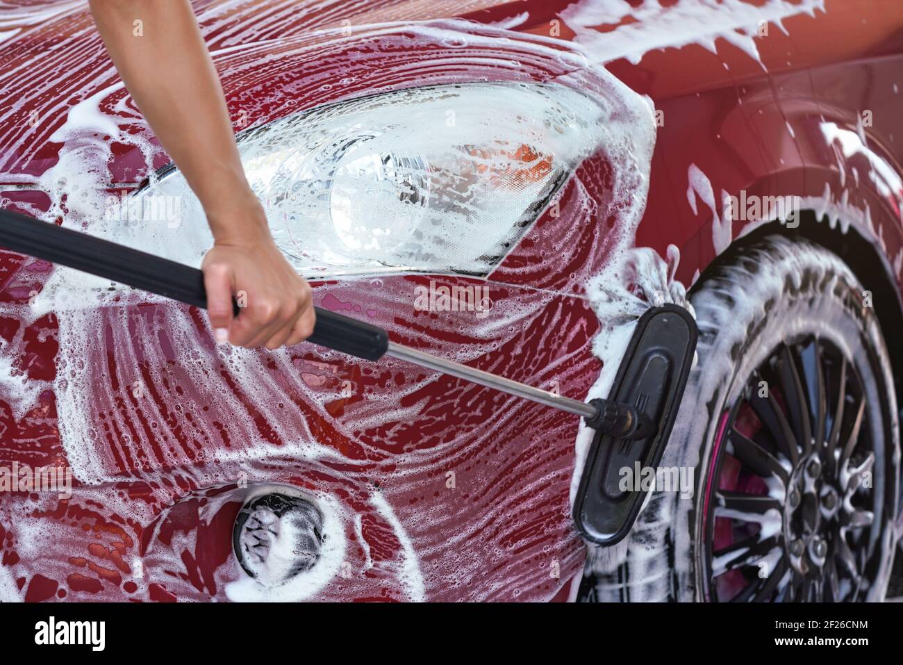 Red car washed in self serve carwash detail on brush moving over front ...