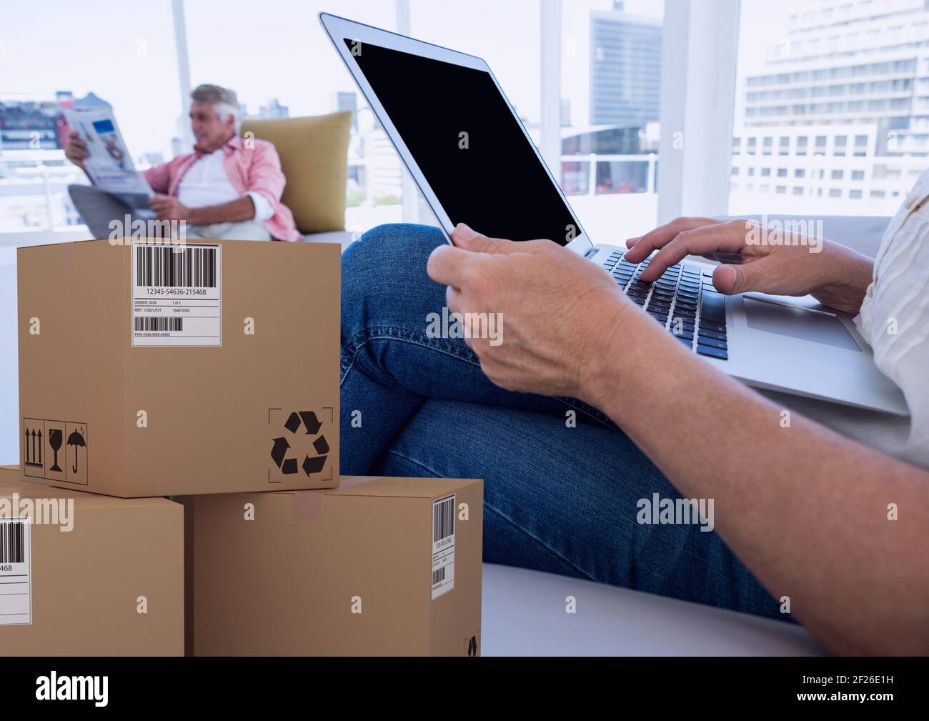 Composition of cardboard boxes man and woman using laptop and reading ...