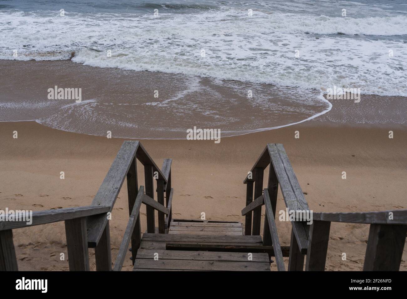 Wooden steps leading to the beach as the waves crash against the tide ...