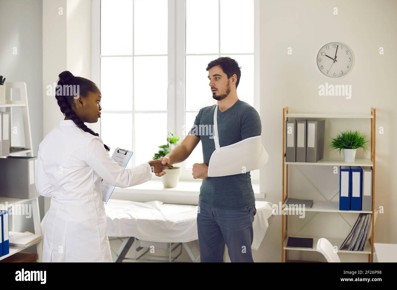 African american doctor greeting caucasian patient with handshake at ...
