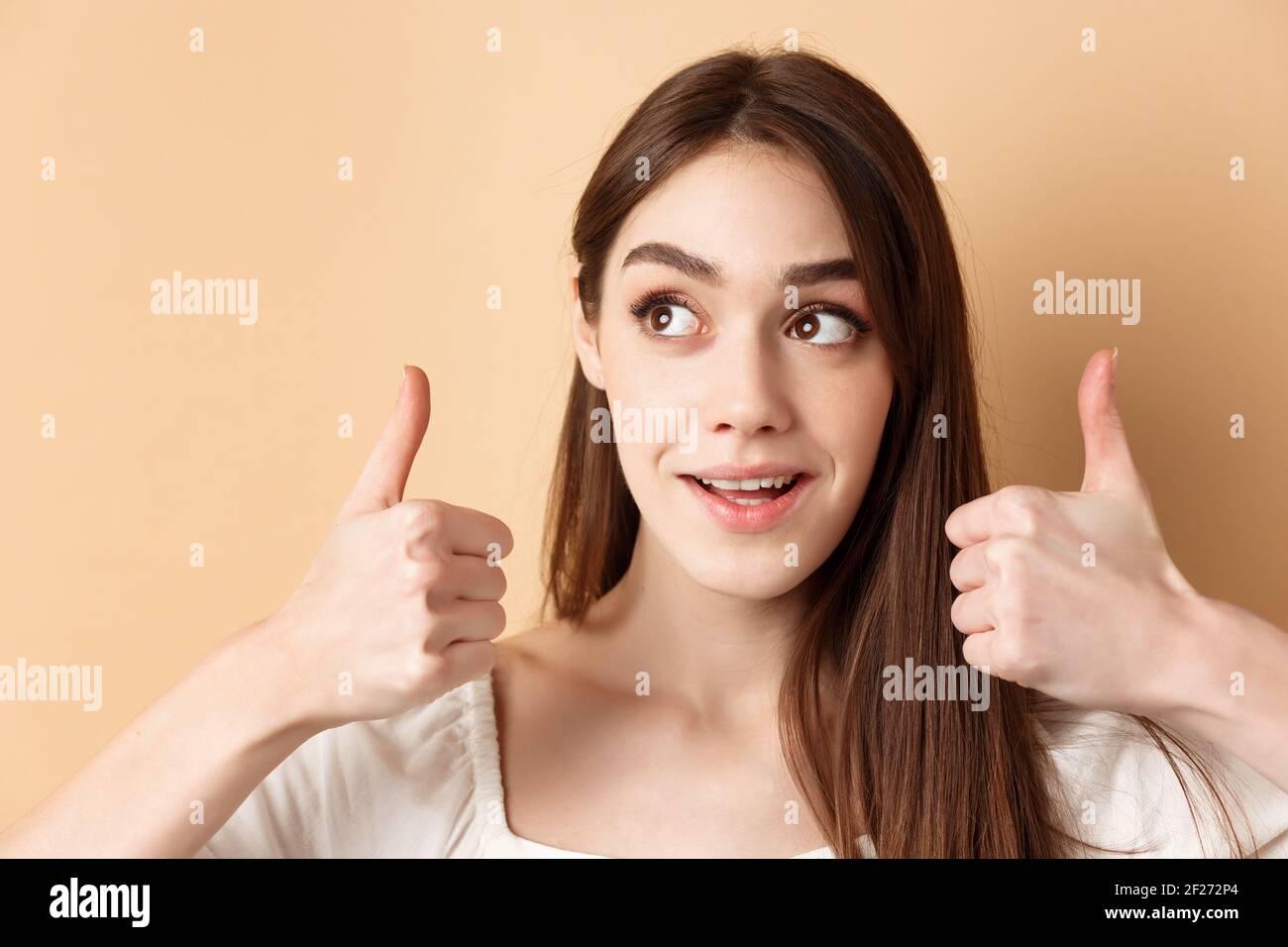 Close up of pretty girl look at upper left corner logo, showing thumbs ...