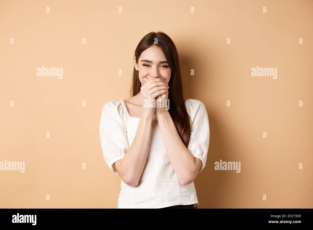 Happy girl laughing and covering mouth with hands, hiding her smile and ...