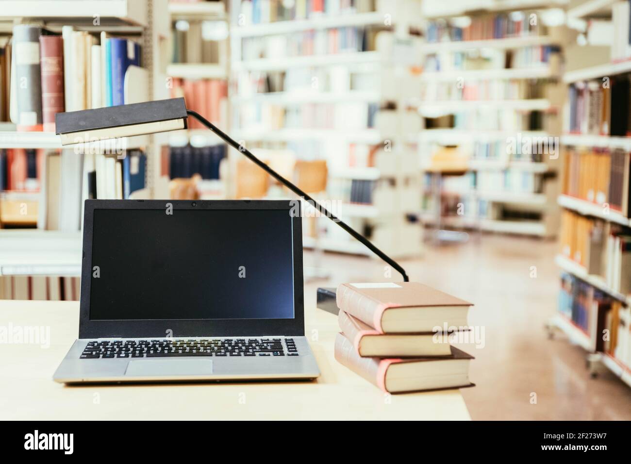 Studying in the university: Laptop on a wooden desk, pile of books and ...