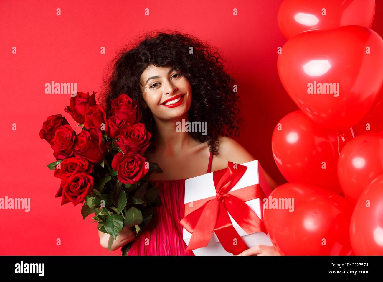 Romantic woman receive bouquet of flowers and gift on holiday, standing ...