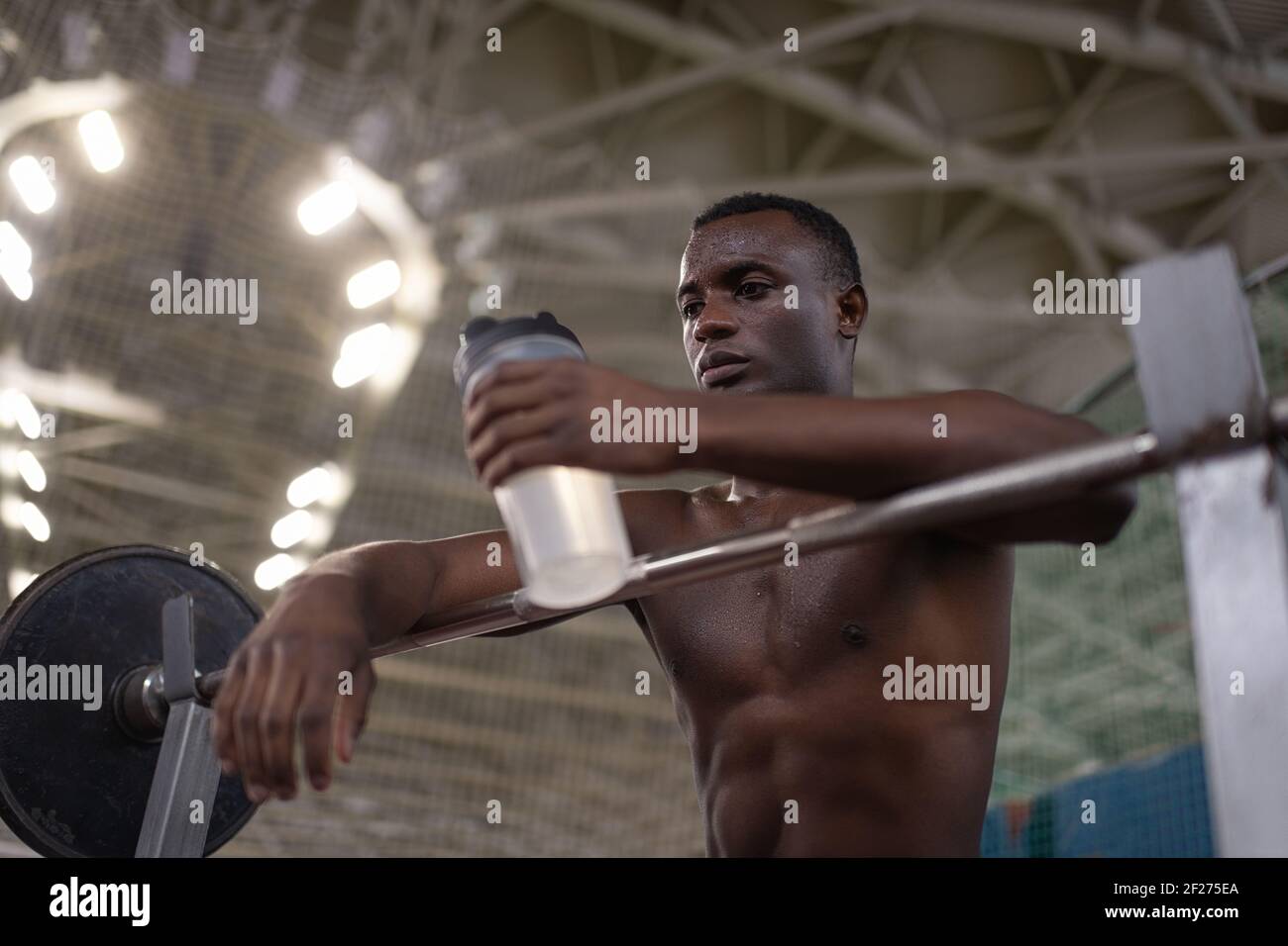 Exhausted black weightlifter with water resting Stock Photo - Alamy
