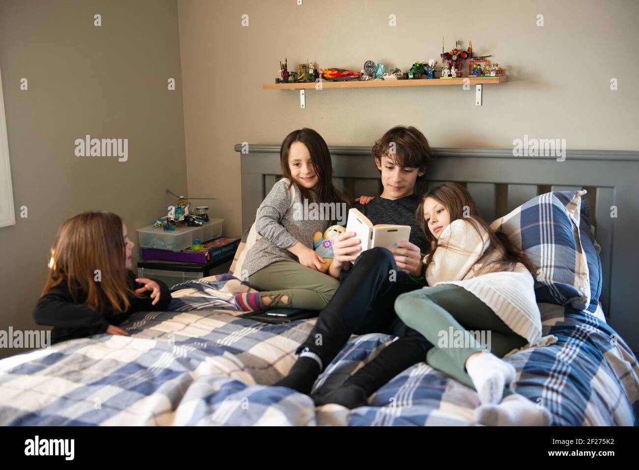 Tween boy reading to his little sisters in bedroom Stock Photo - Alamy