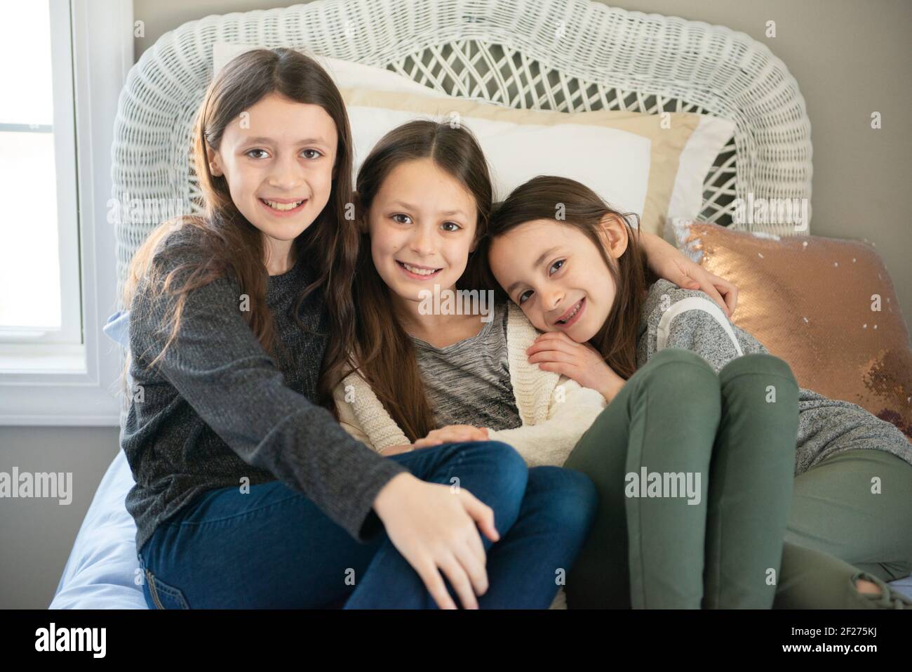 Three happy sisters cuddling on a bed together Stock Photo - Alamy