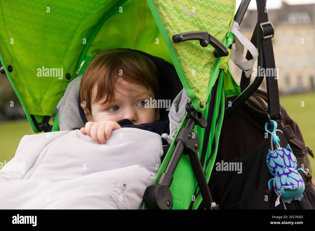 Cute, redhead, blue-eyed baby boy sitting on a green pushchair Stock ...